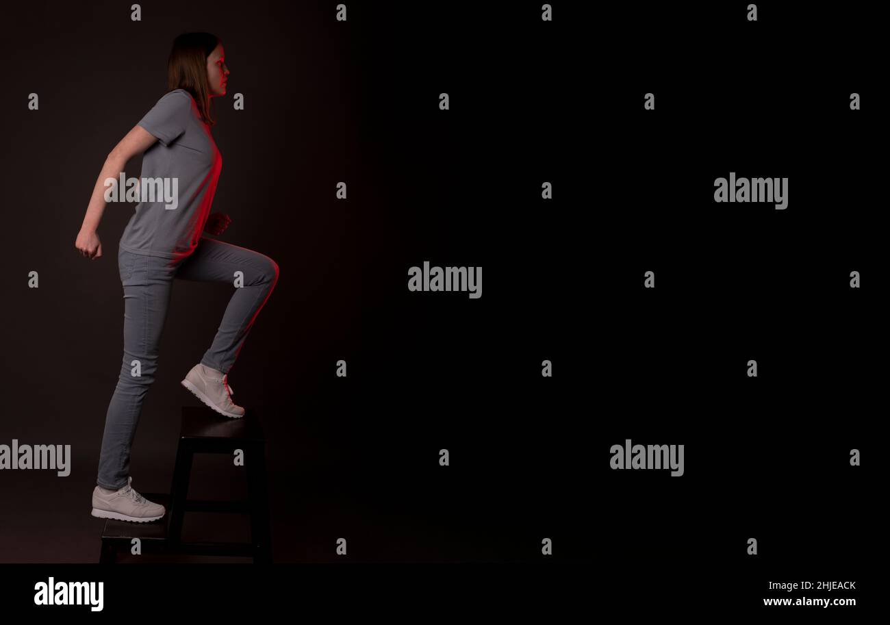 Young woman walking up stairs, running upstairs on black background ...