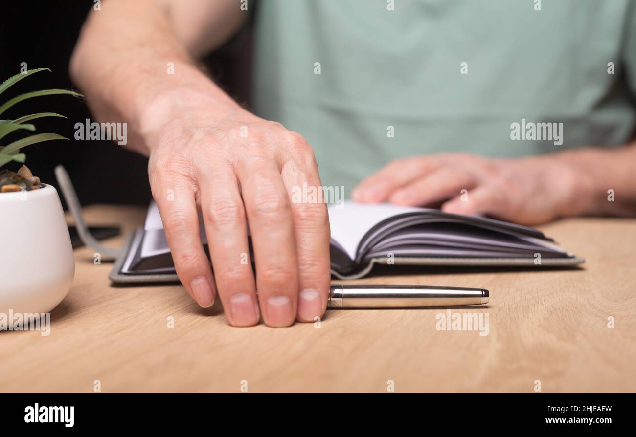 Male hands starting to plan his day, writing his schedule in organizer ...