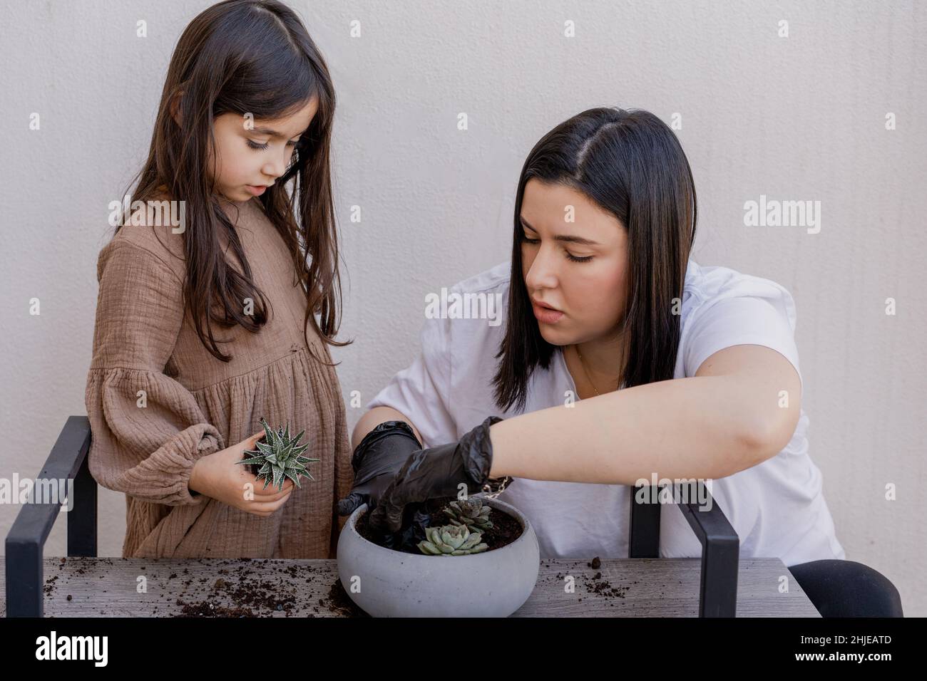 Mother and daughter planting in home garden. Beautiful young mom and ...