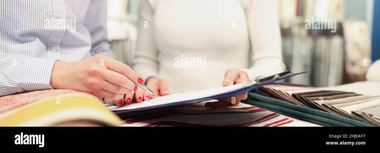 Two women choose fabrics and place order in store closeup Stock Photo ...