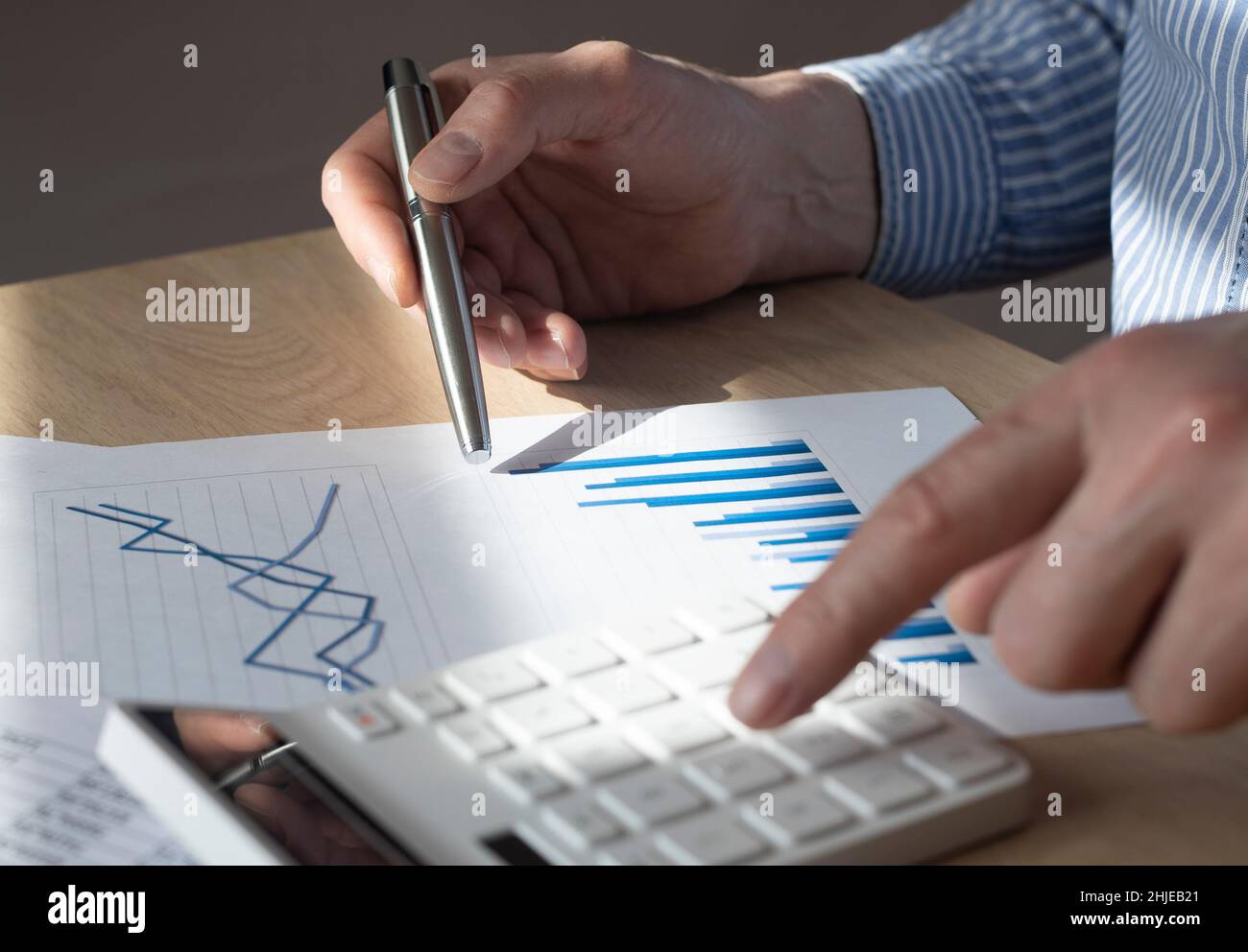 Male hand at desk with financial document with graph of growing trend ...