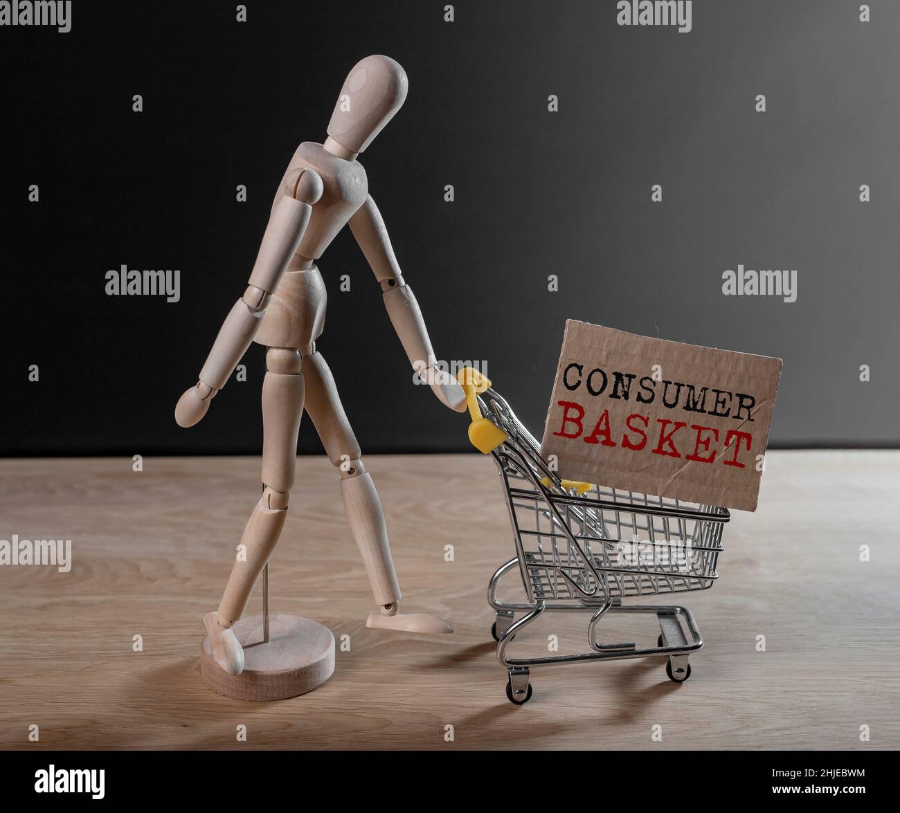 Consumer basket text in shopping cart pushed by wooden doll Stock Photo ...
