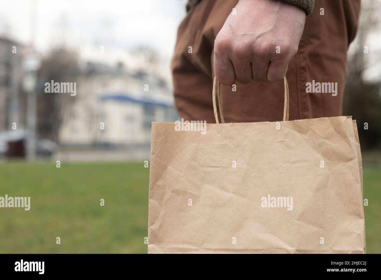 Male hand closeup holding organic brown craft packet in hand on city ...