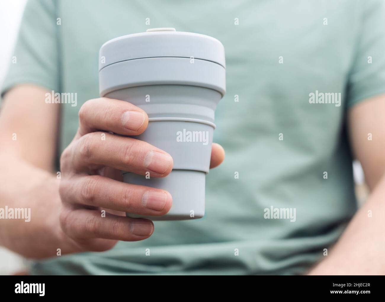 Collapsible cup for takeaway coffee or tea. Male hand with sustainable ...