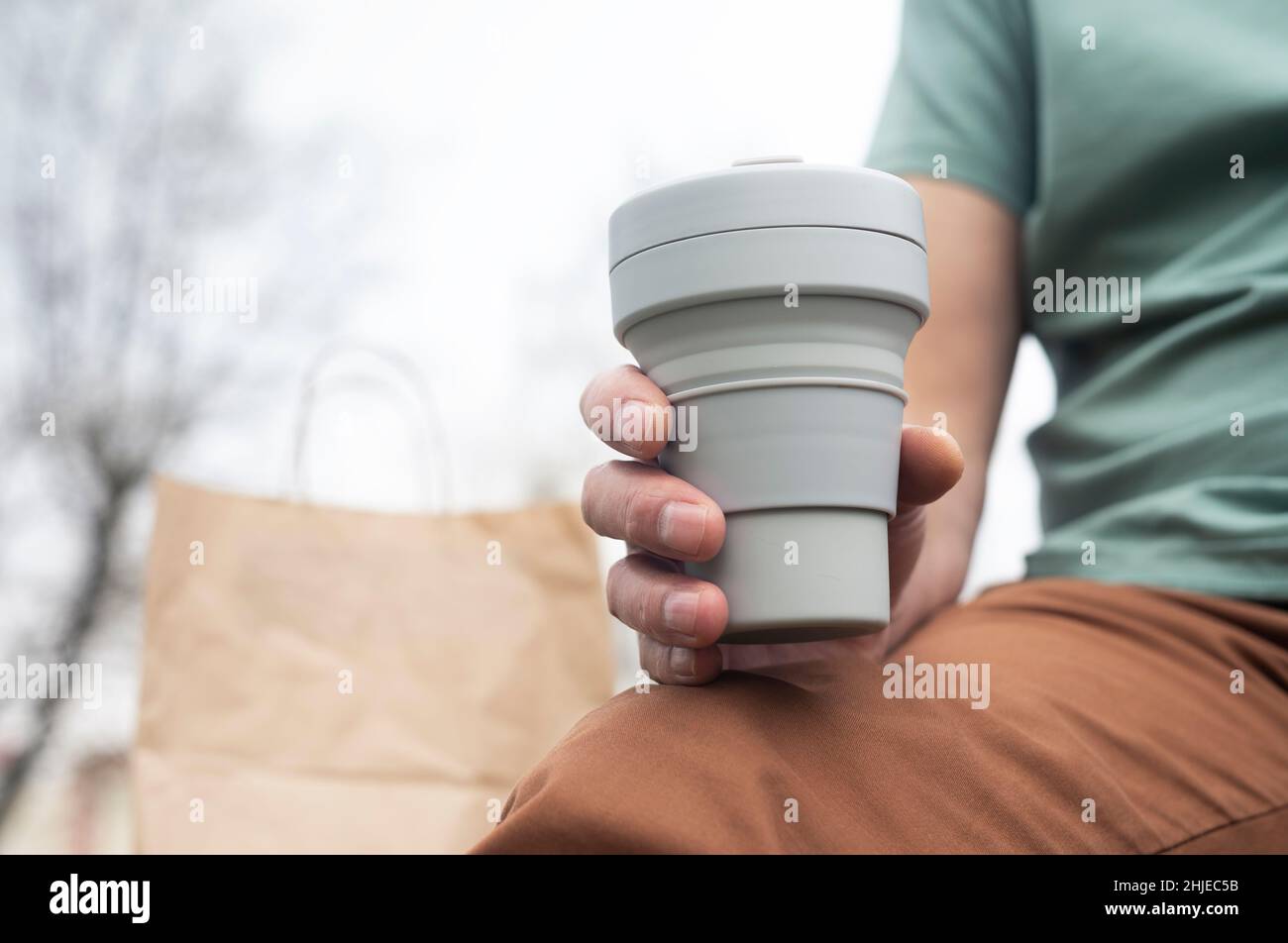 Collapsible cup for takeaway coffee or tea. Male hand with sustainable ...