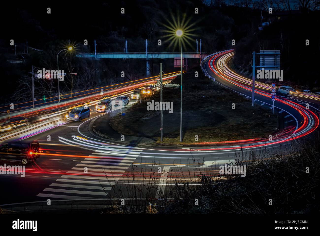 Long exposure shot of a turning road illuminated with traffic lights in ...