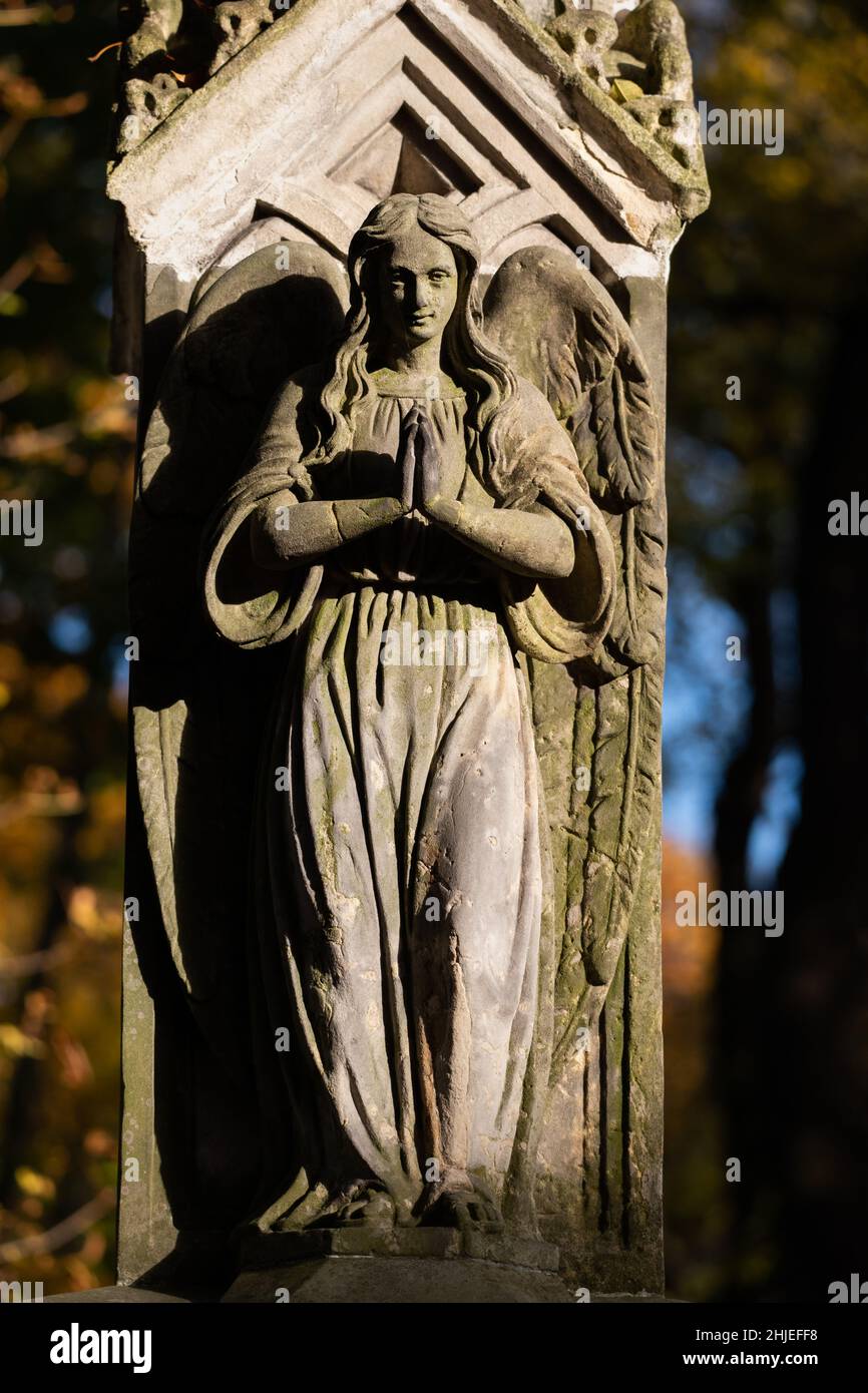 Angel with praying hands and heartening smile, old stone sculpture of ...