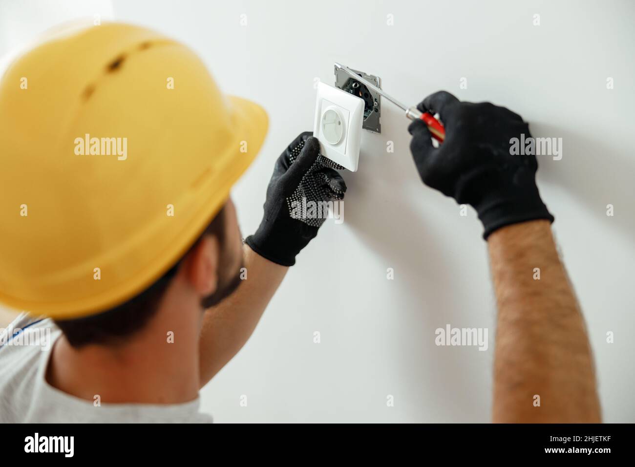 Professional electrician in uniform using screwdriver while installing ...