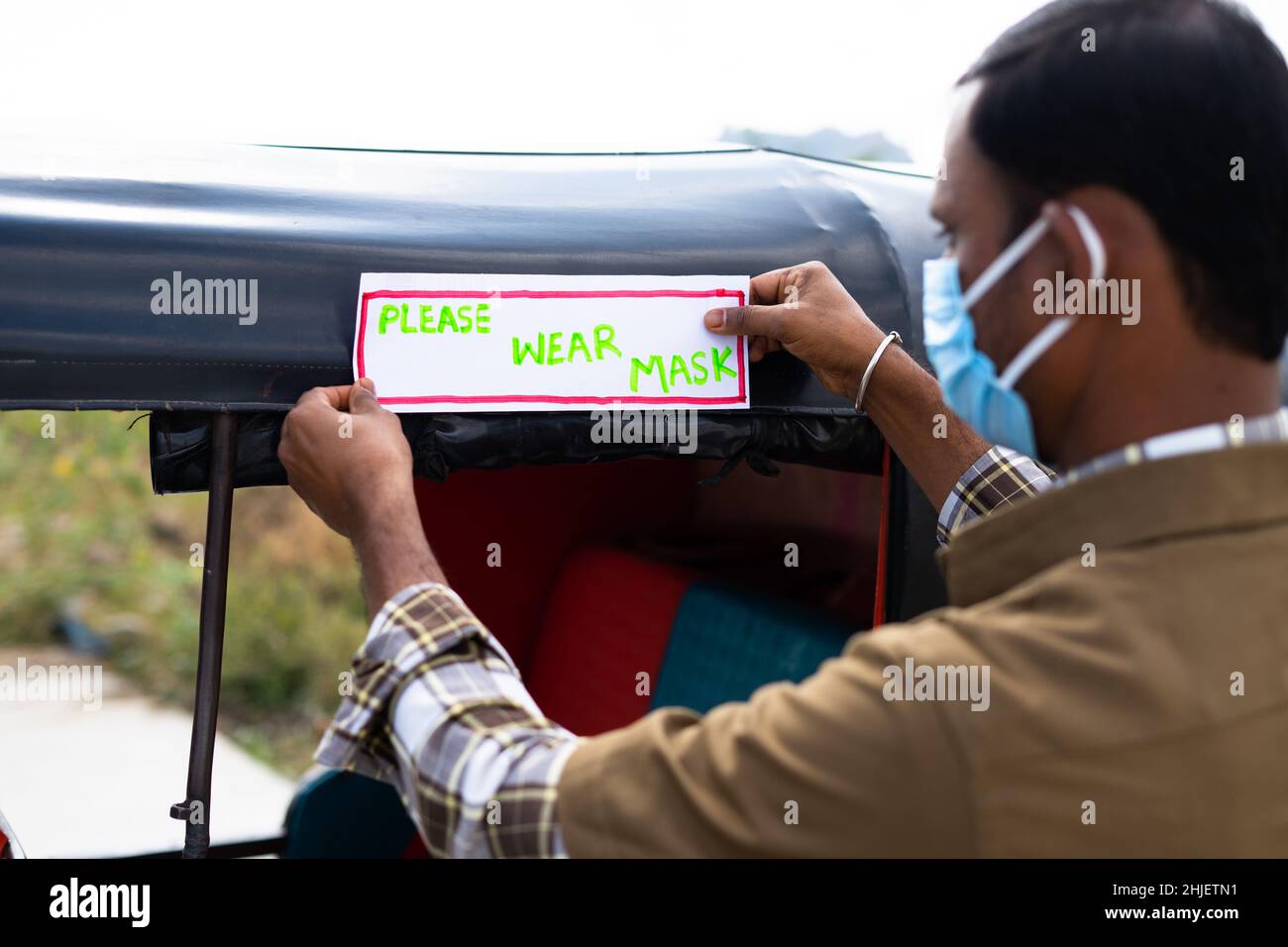 Focus on notice, Auto driver with medical face mask pasting Please wear ...