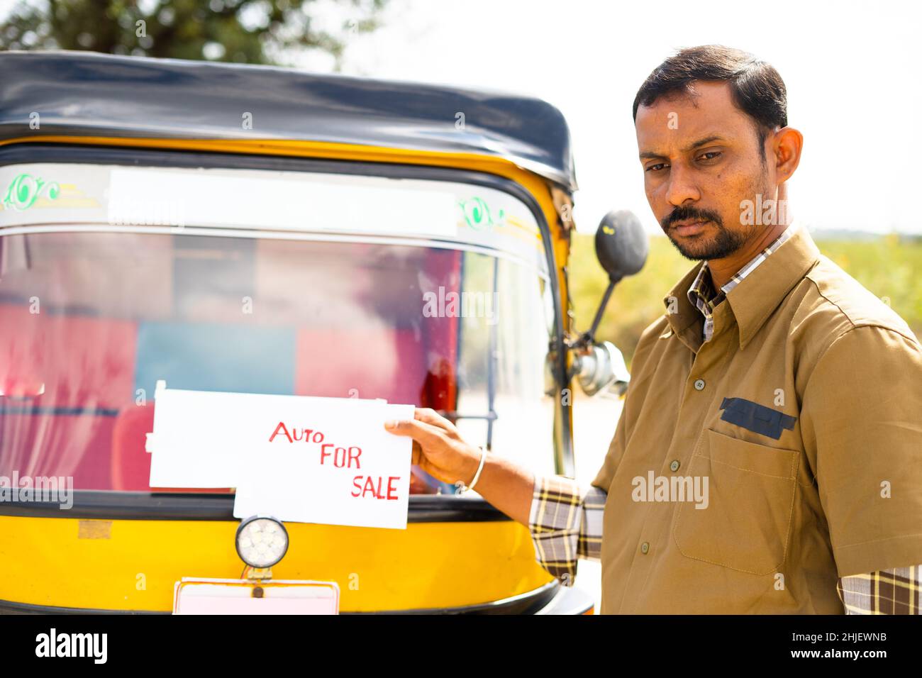 sad auto driver placing auto rikshaw for sale sign board in front of ...