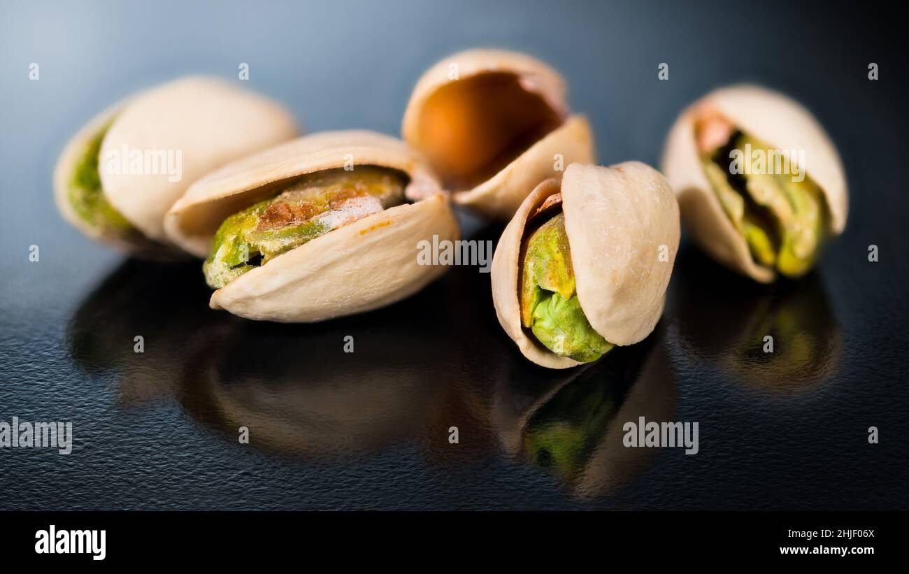 Yummy roasted salted pistachio nuts group with reflection on a black ...