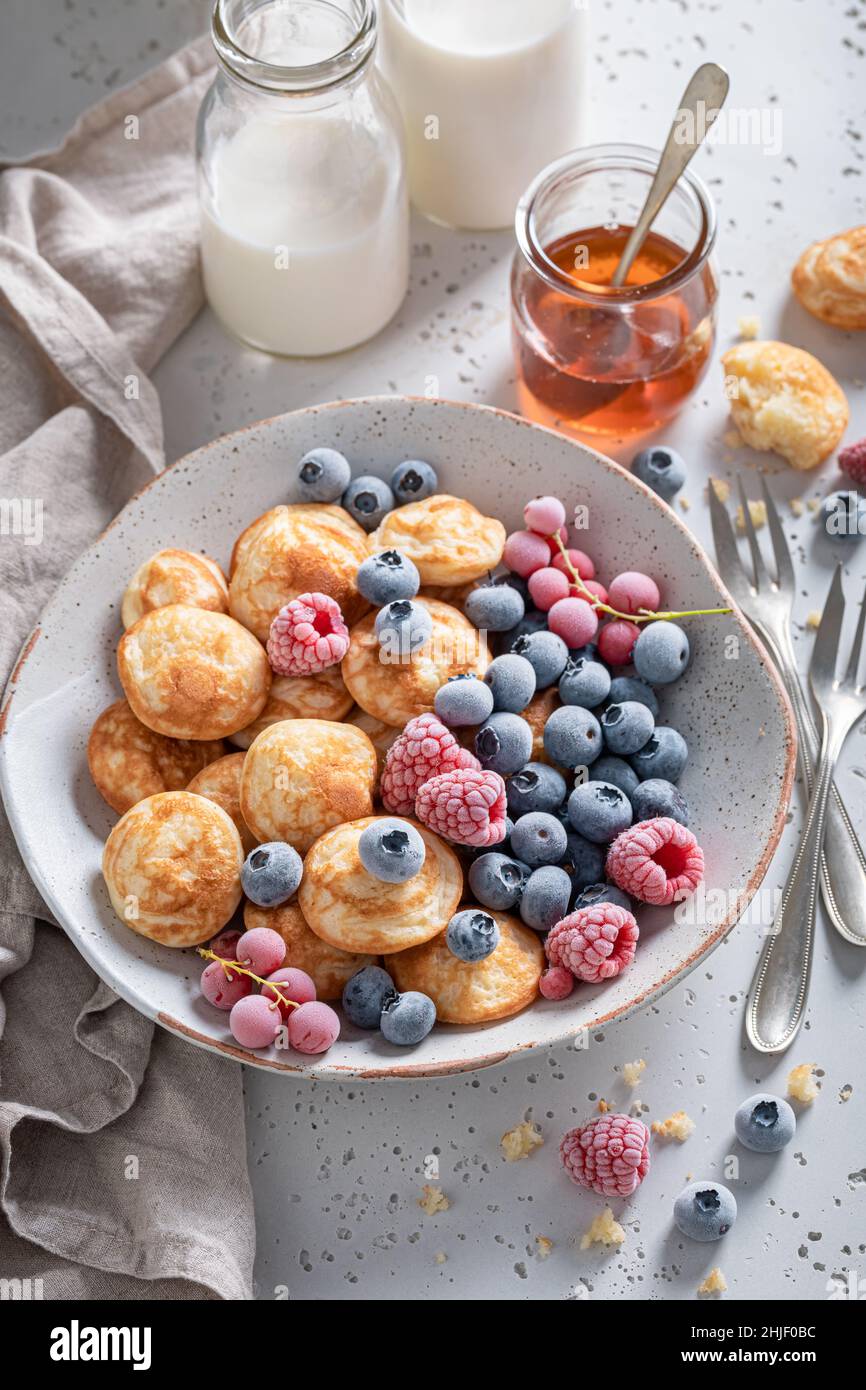 Dutch poffertjes with yoghurt and frozen berries. Poffertjes with ...