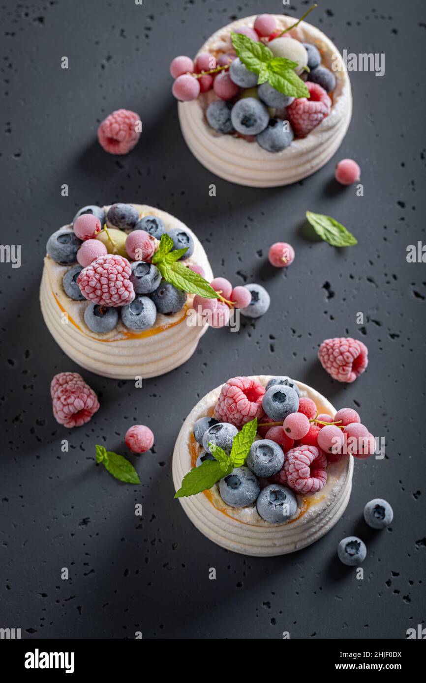 Sweet mini Pavlova dessert with whipped cream and frozen fruit. Pavlova ...