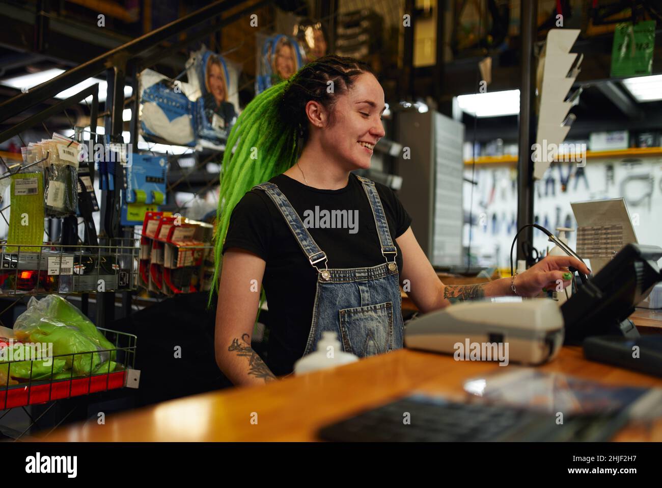 Cheerful young female cashier in casual clothes with informal hairstyle ...