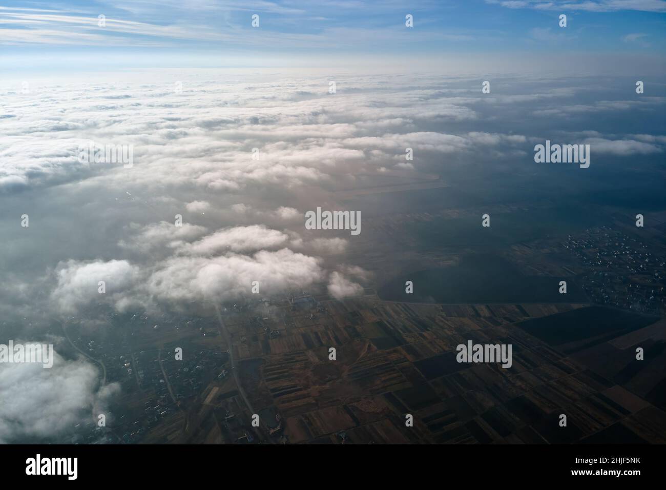 Aerial view from high altitude of distant city covered with puffy ...