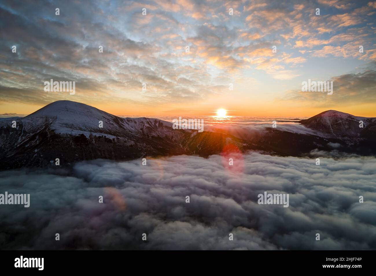 Aerial view of vibrant sunrise over white dense clouds with distant ...