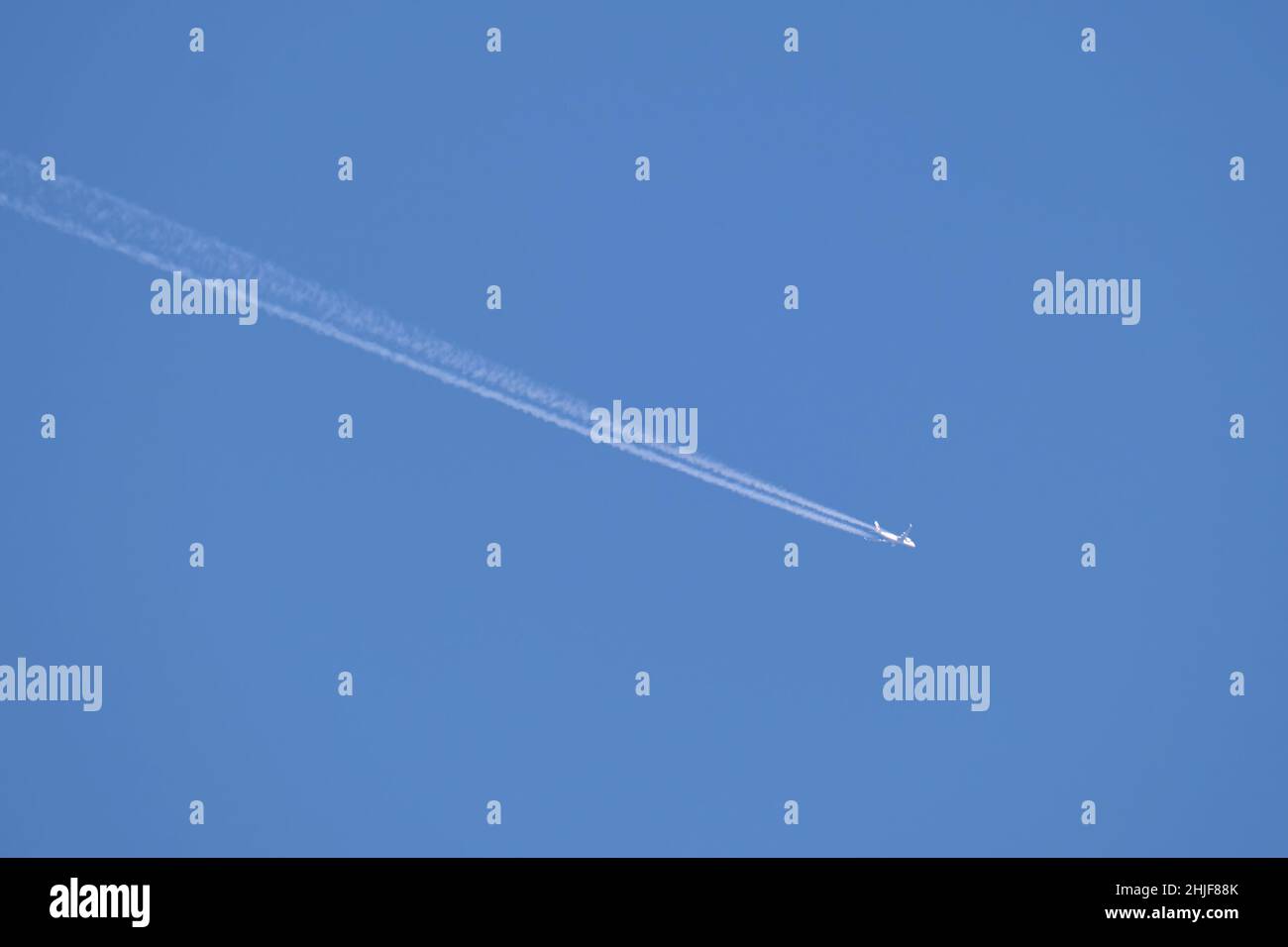 Distant passenger jet plane flying on high altitude on clear blue sky ...