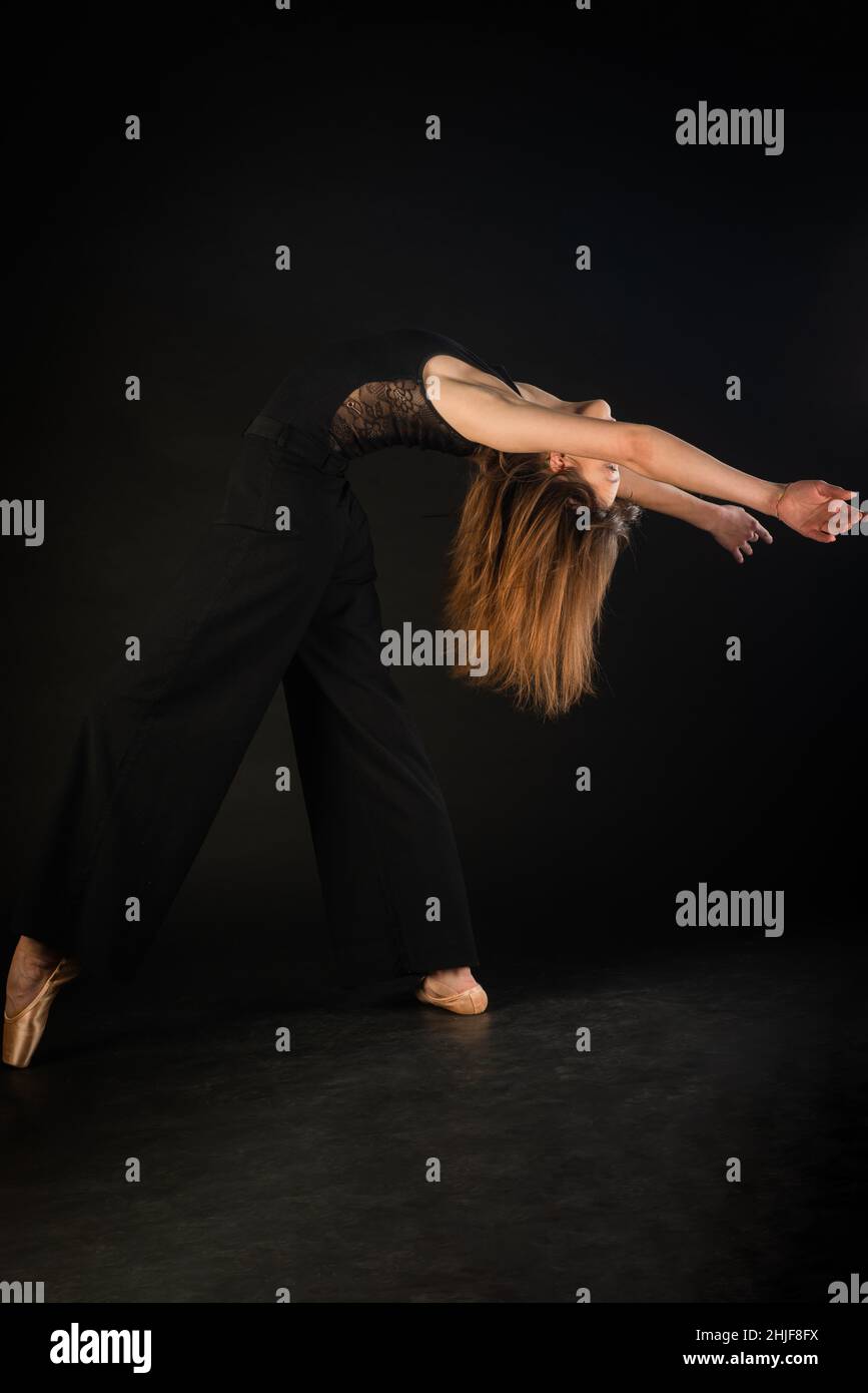 Beautiful ballerina is posing while bending her back on black ...