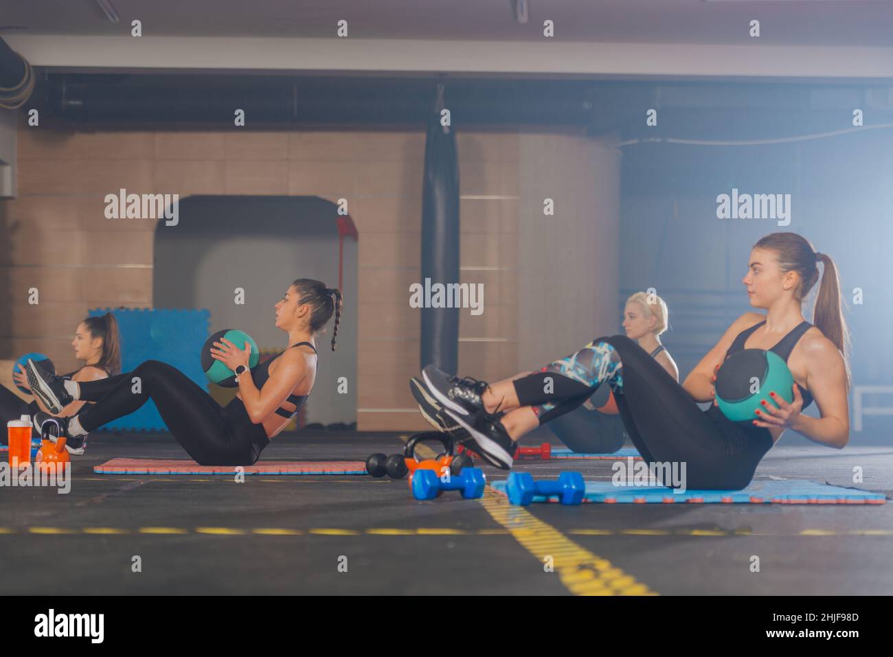 Side view of beautiful young women exercising russian twist with ...