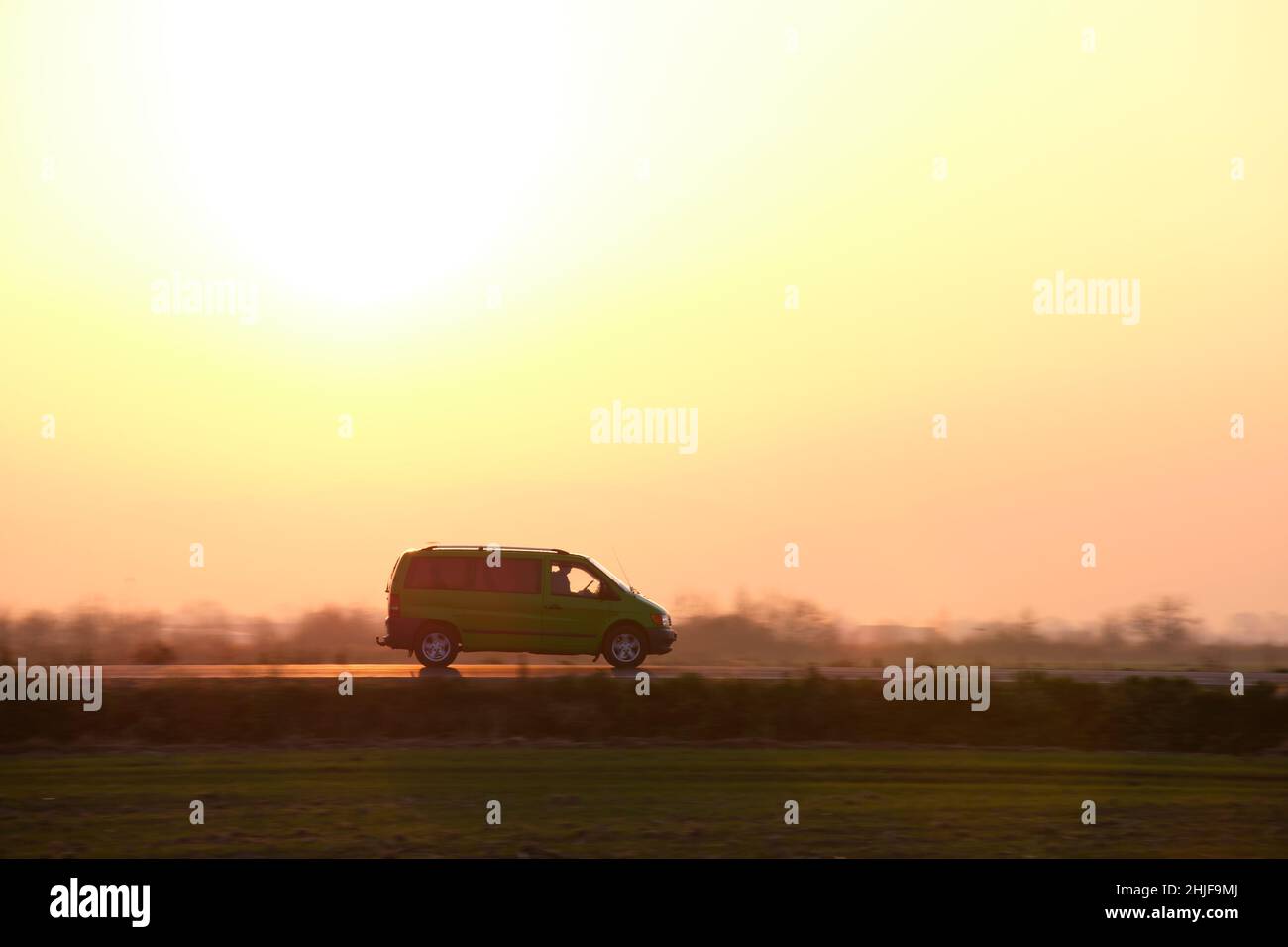 Passenger van driving fast on intercity road at sunset. Highway traffic ...