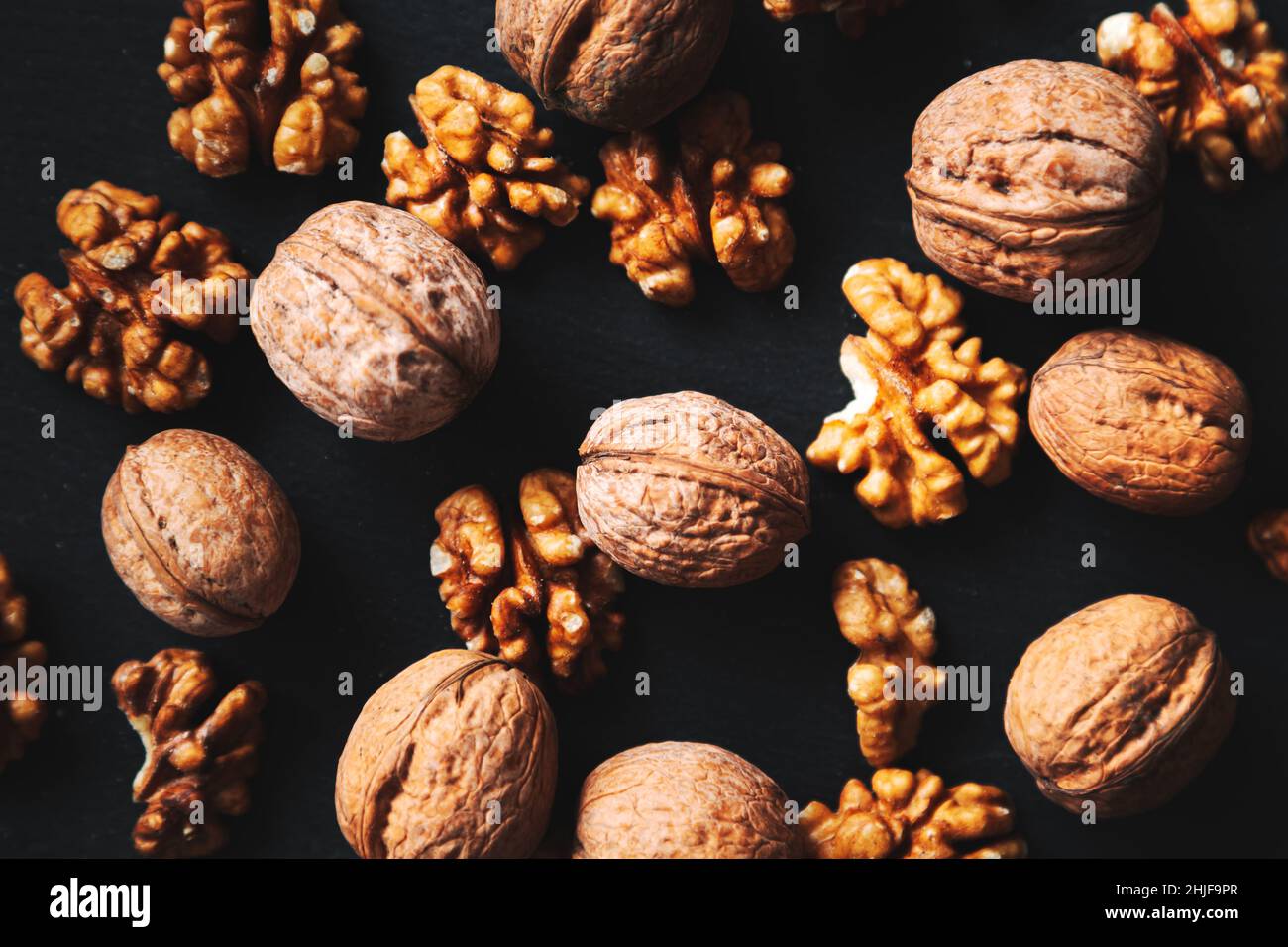 Whole and peeled walnuts on a black background. Close-up, flat lay, top ...