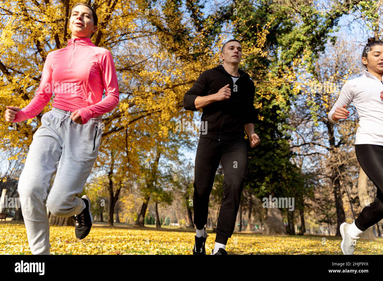 Three amazing and attractive fit friends are running and smiling ...
