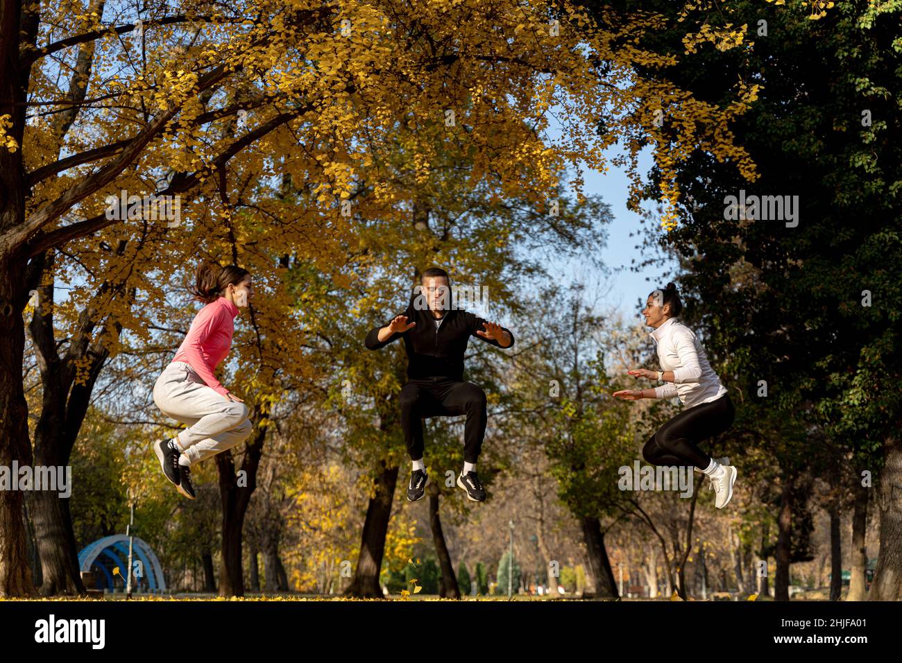 Three attractive and amazing fit friends are jumping high together ...