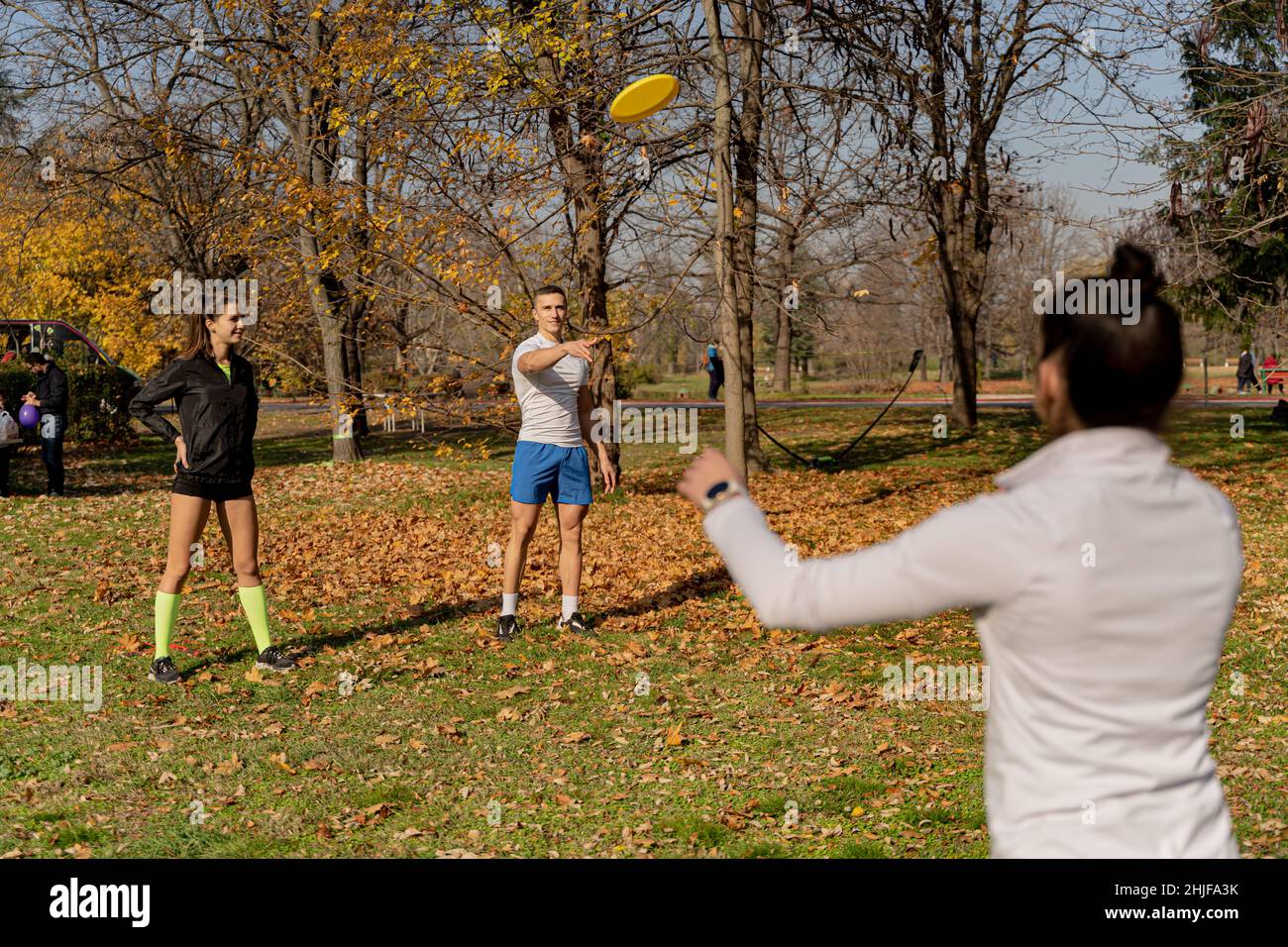 Three attractive and amazing fit friends are playing frisbee and ...
