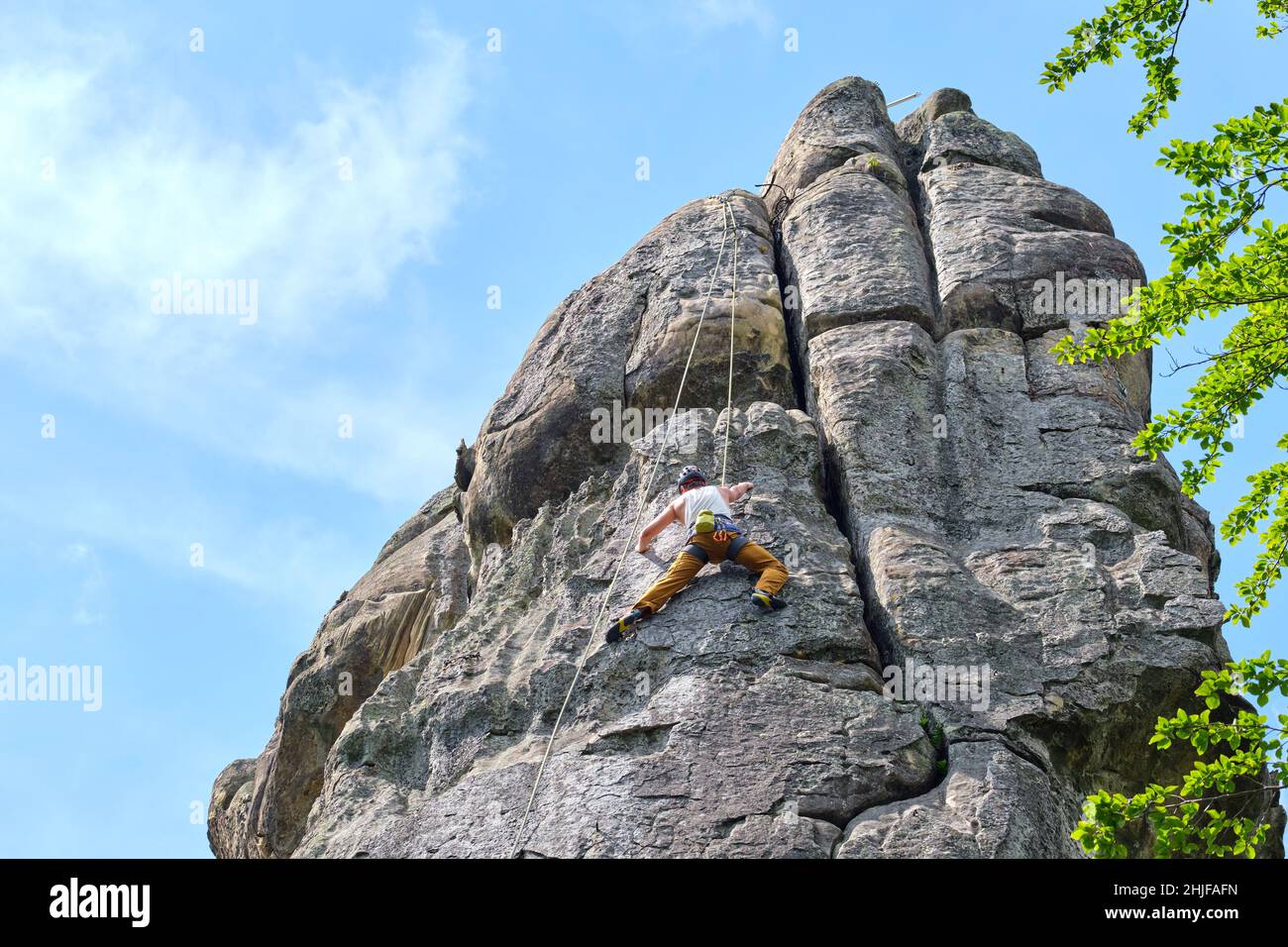 Strong male climber climbing steep wall of rocky mountain. Sportsman ...
