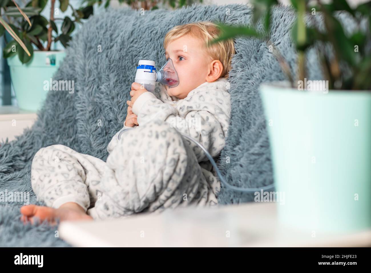 Cute baby boy makes inhalation with a nebulizer equipment. Sick child ...
