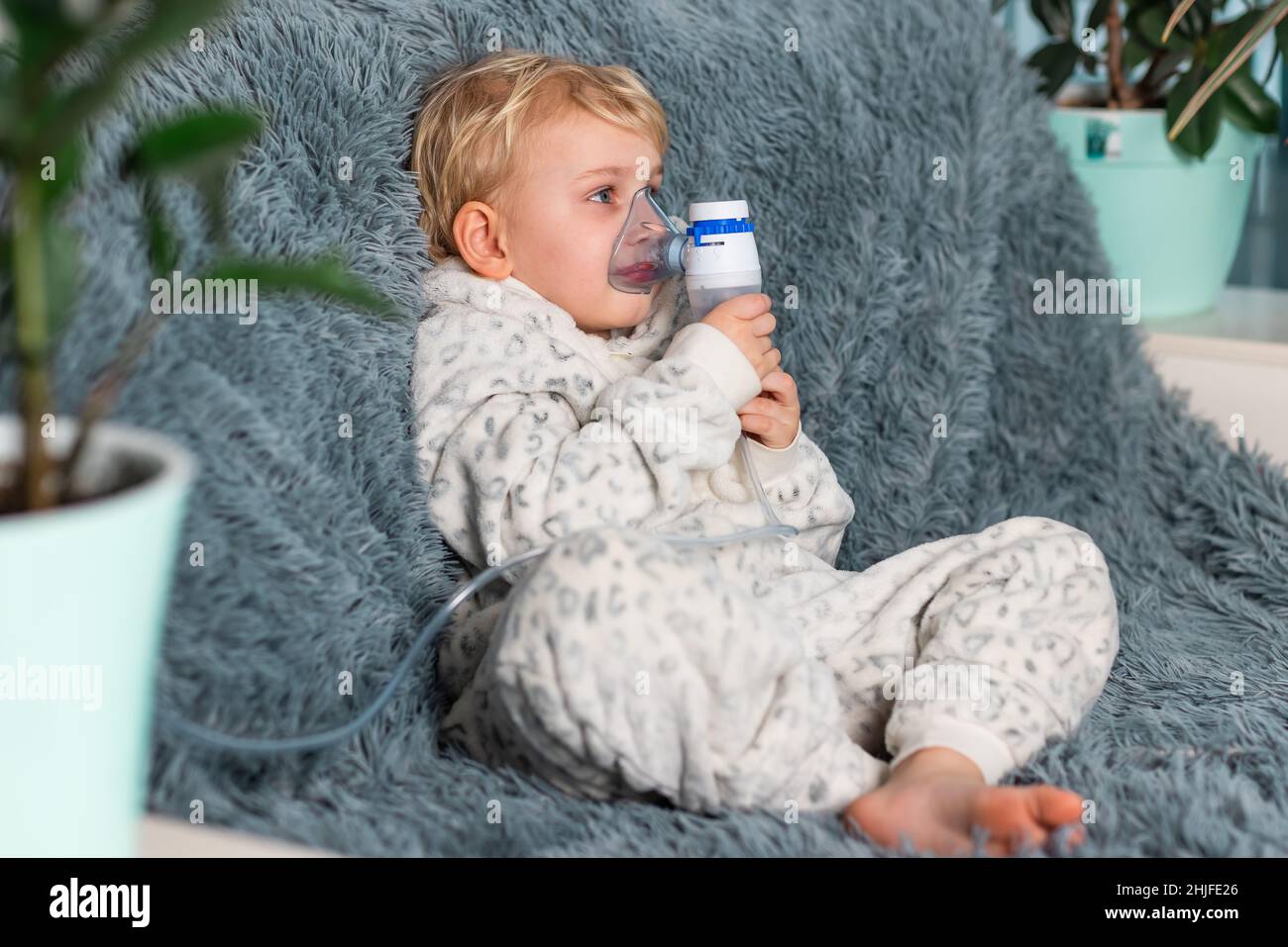 Cute baby boy makes inhalation with a nebulizer equipment. Sick child ...