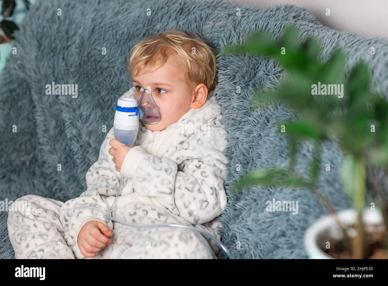 Cute baby boy makes inhalation with a nebulizer equipment. Sick child ...