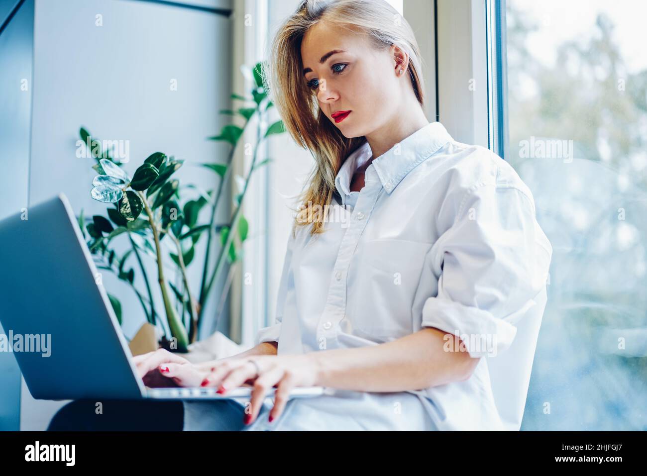 Young female with laptop near window Stock Photo - Alamy