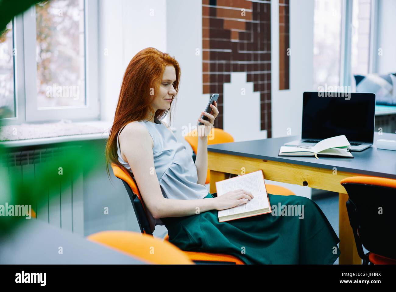 Woman using smartphone while reading book and using computer Stock ...