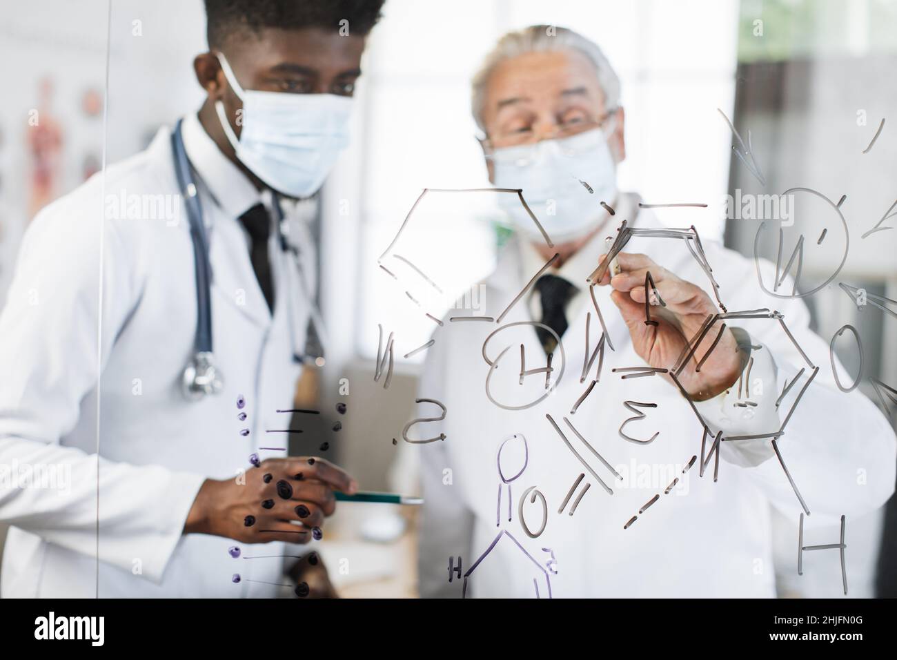 African american and caucasian scientists in white lab coats and masks ...