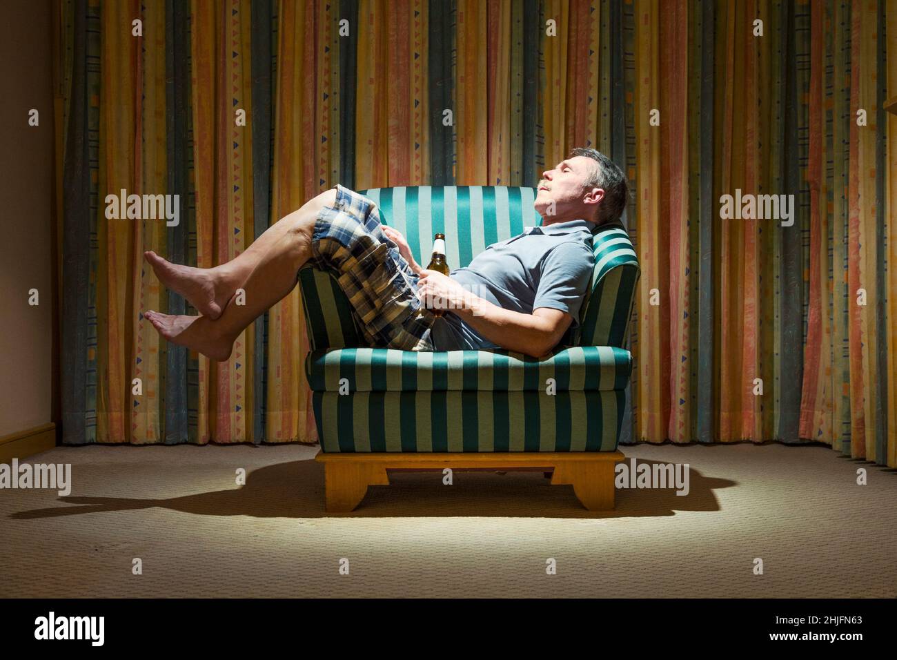 Elderly tourist with a bottle of beer is dozing hotel chair reclining ...