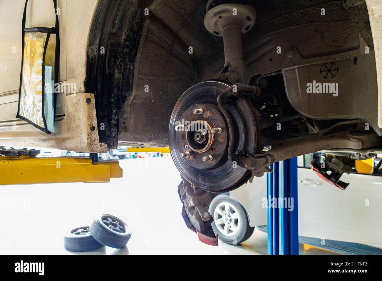 Damaged car and dirty disc brake lifting for maintenance in garage ...
