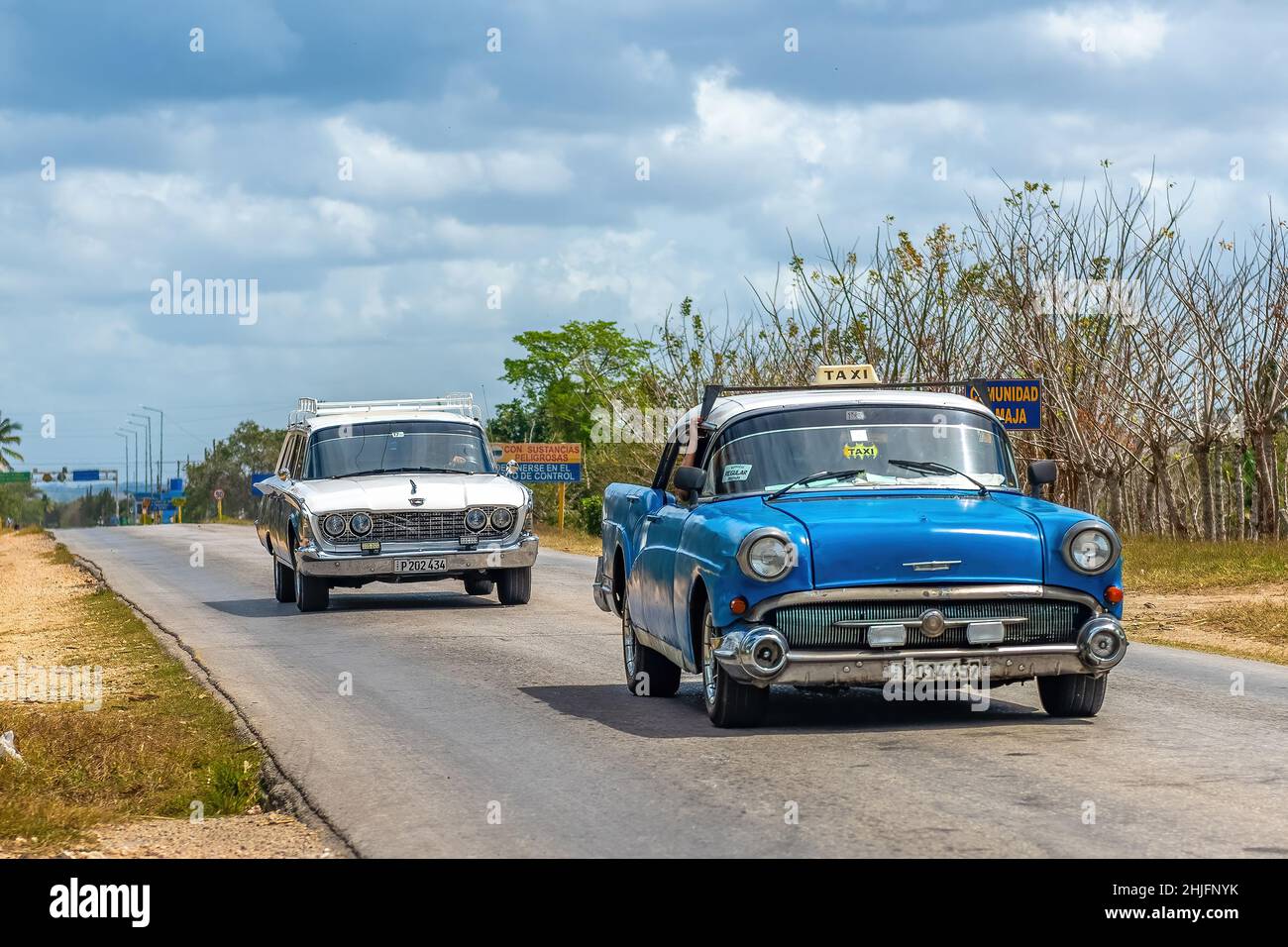 Vintage American car driving on a rural asphalt road. It has a Taxi ...
