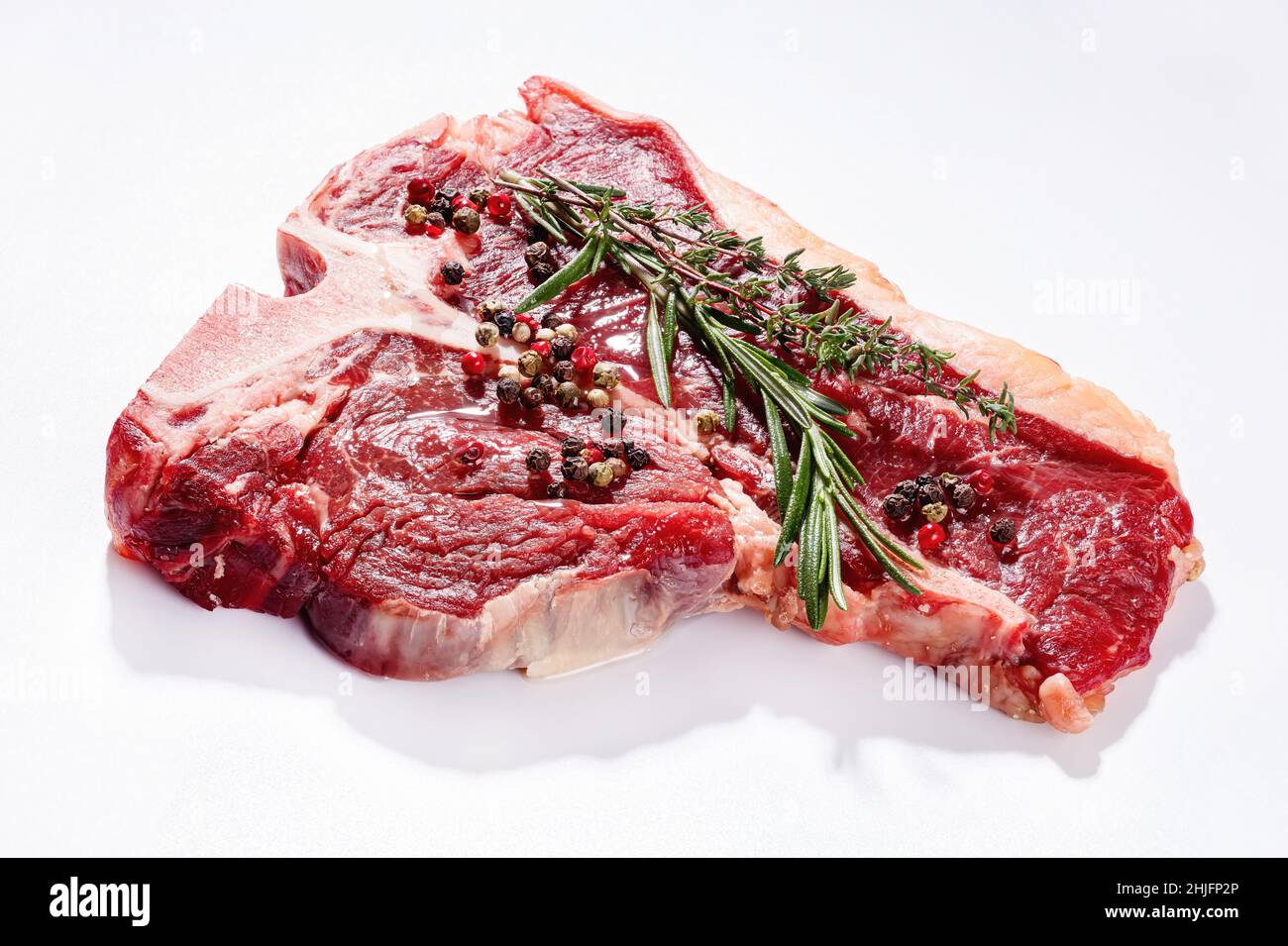 uncooked t-bone beef steak with thyme, rosemary and peppercorn on a ...