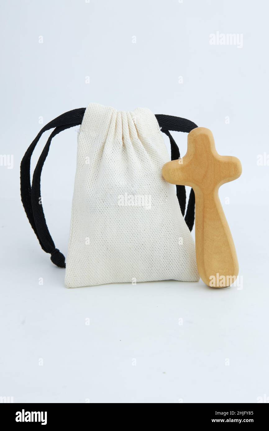 Photo showing a wooden cross and a white cloth gift bag on a white ...