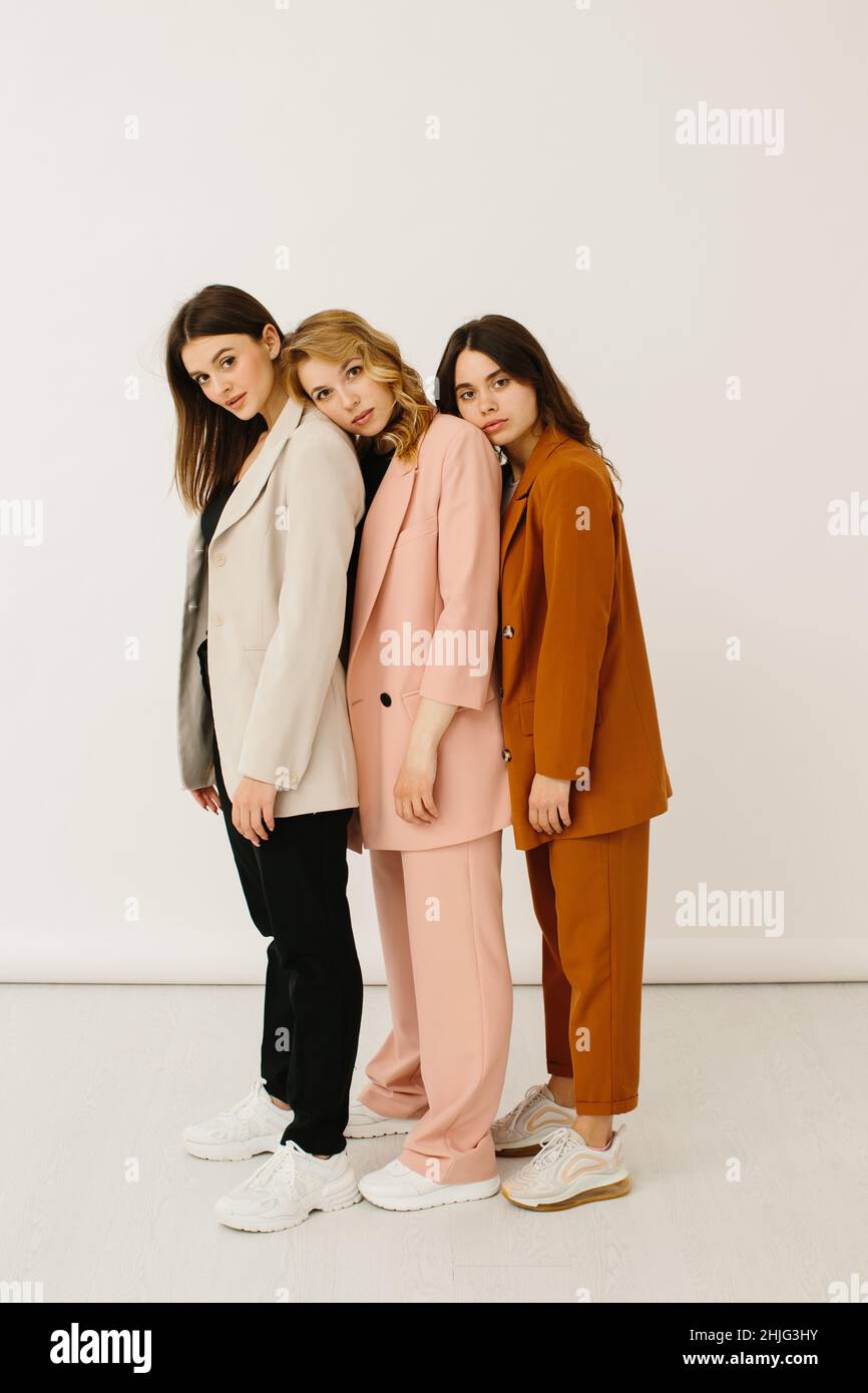 Stylish young women in pastel outfits standing together, fashion ...