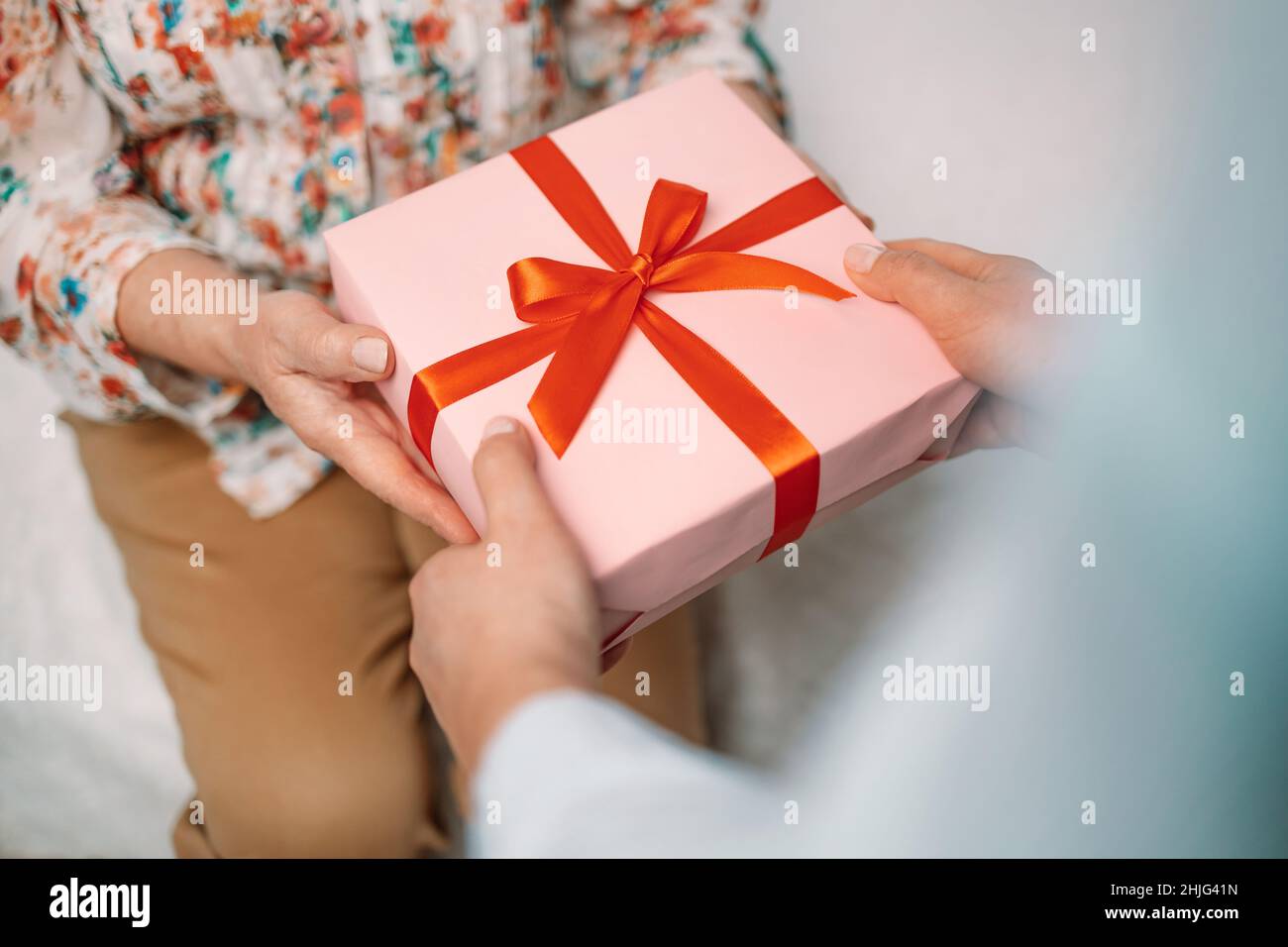 Close up image of a woman giving a mom a pink gift box. Happy Mothers ...