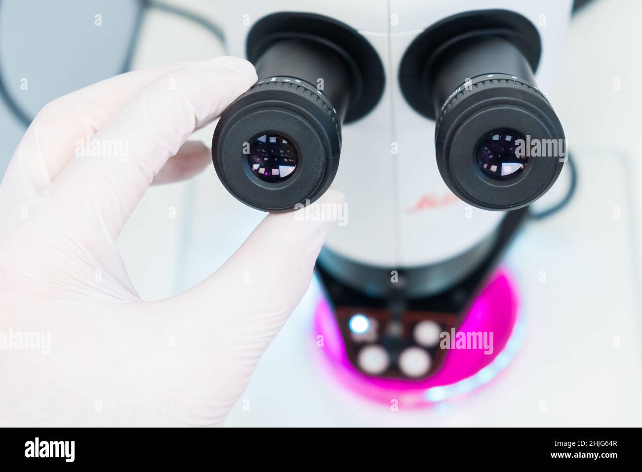 Close up scientist hand sets up a microscope to analyze the sample ...