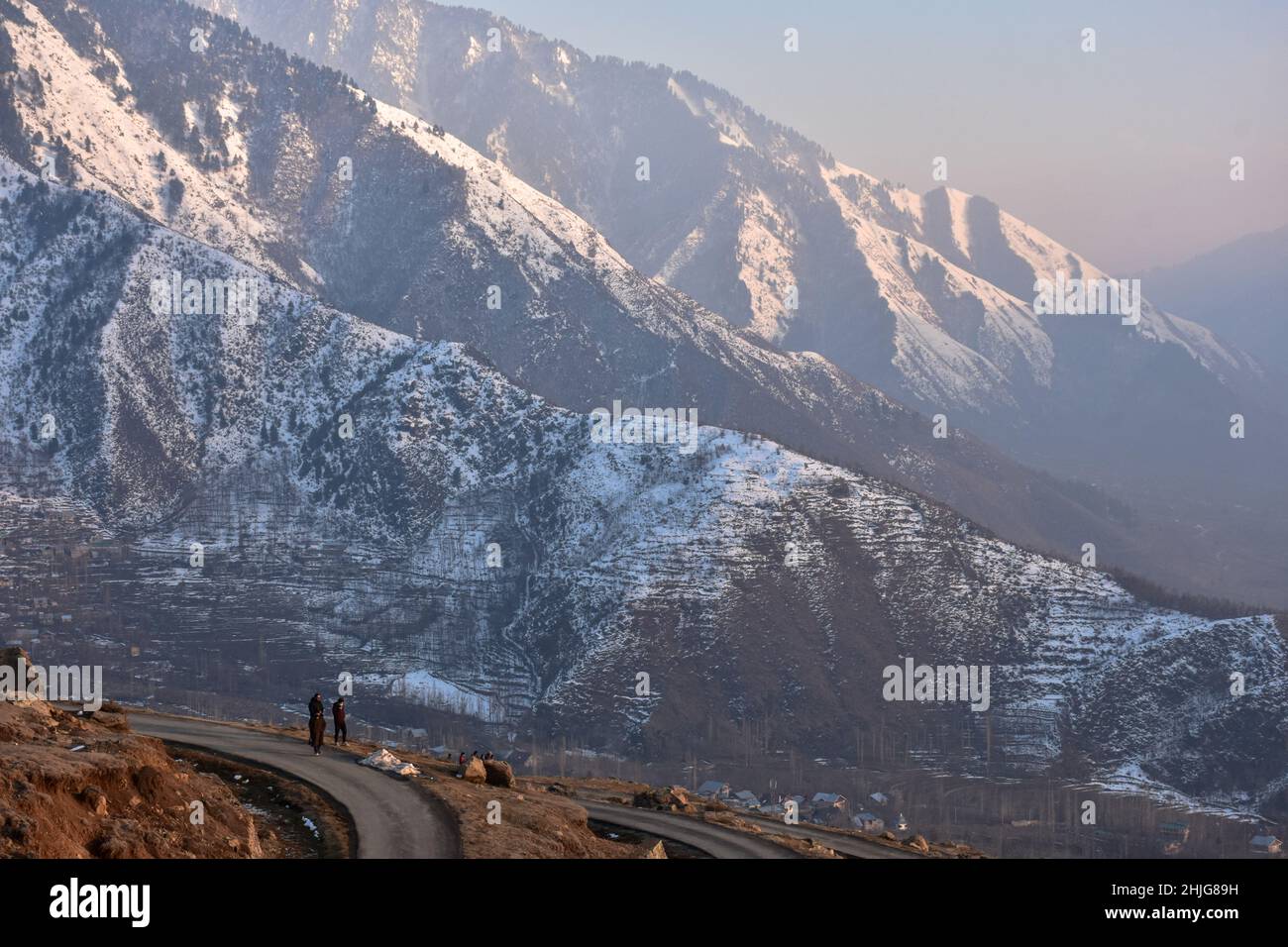 Kashmiri residents walk through a road during a cold winter evening on ...
