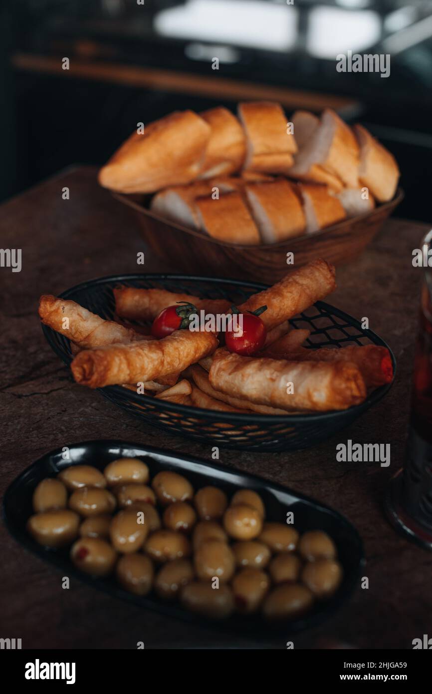 Fresh pastries, green olives and white bread on the table. Traditional ...