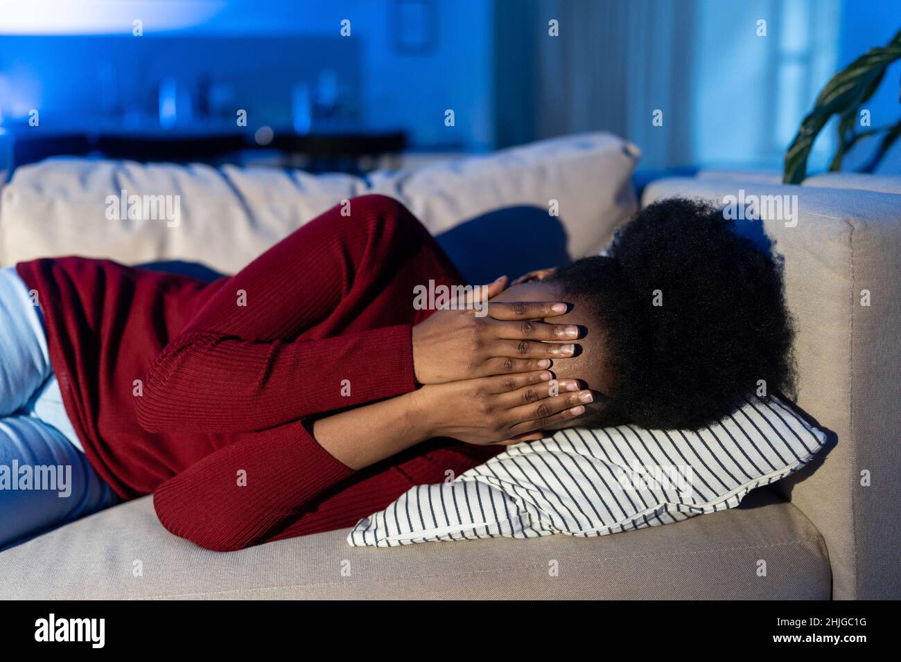 Depressed african woman lying on sofa crying alone at home, suffering ...