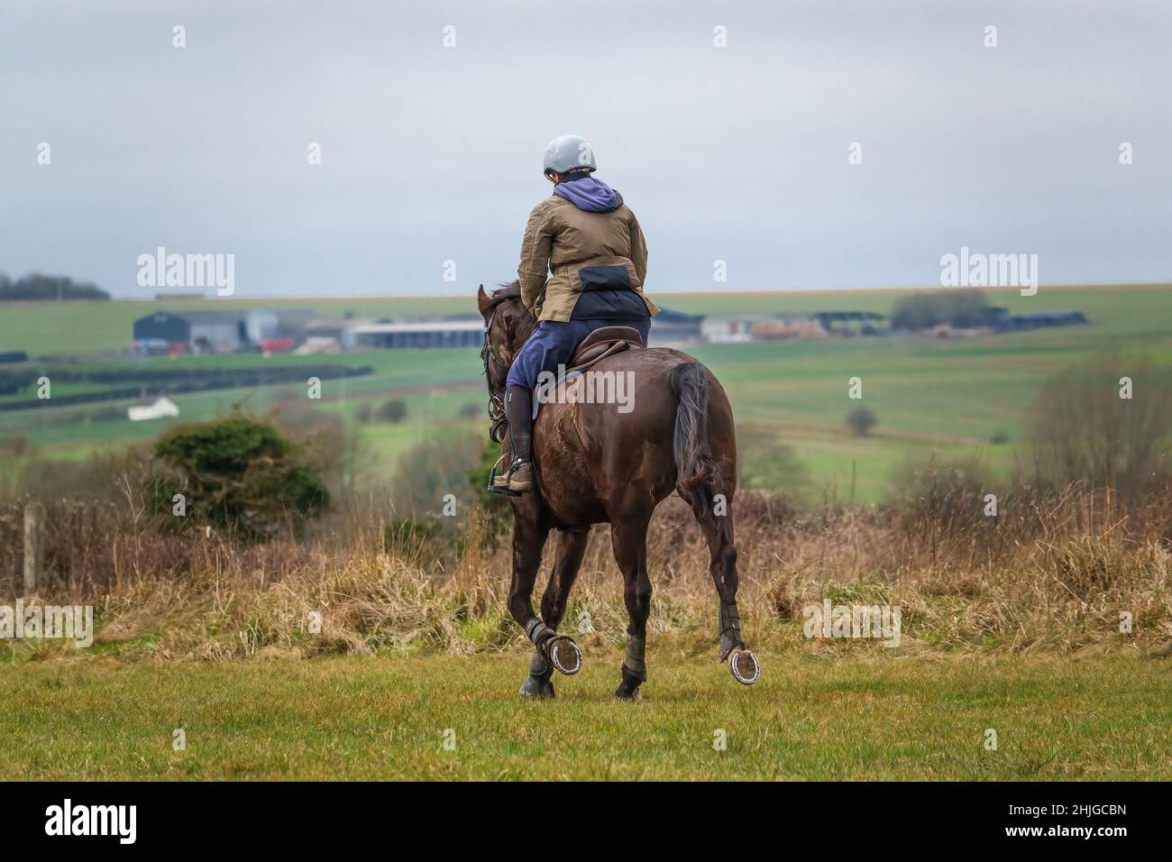 lady horse riding in open countryside under a blue grey cloud winter ...