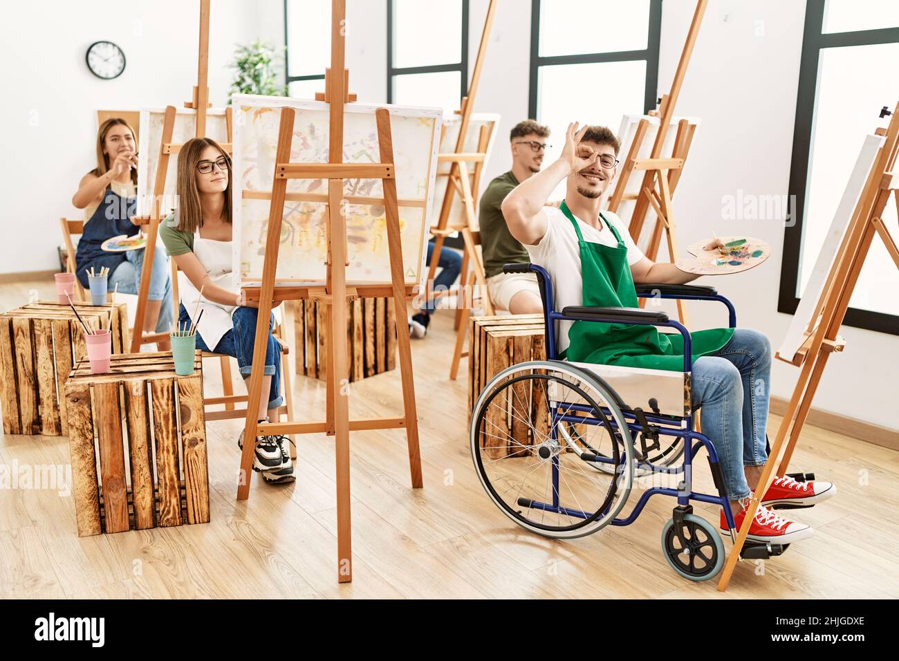 Young disabled man sitting on wheelchair drawing at art studio smiling ...