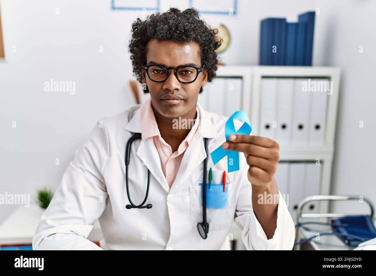 African doctor man holding blue ribbon thinking attitude and sober ...