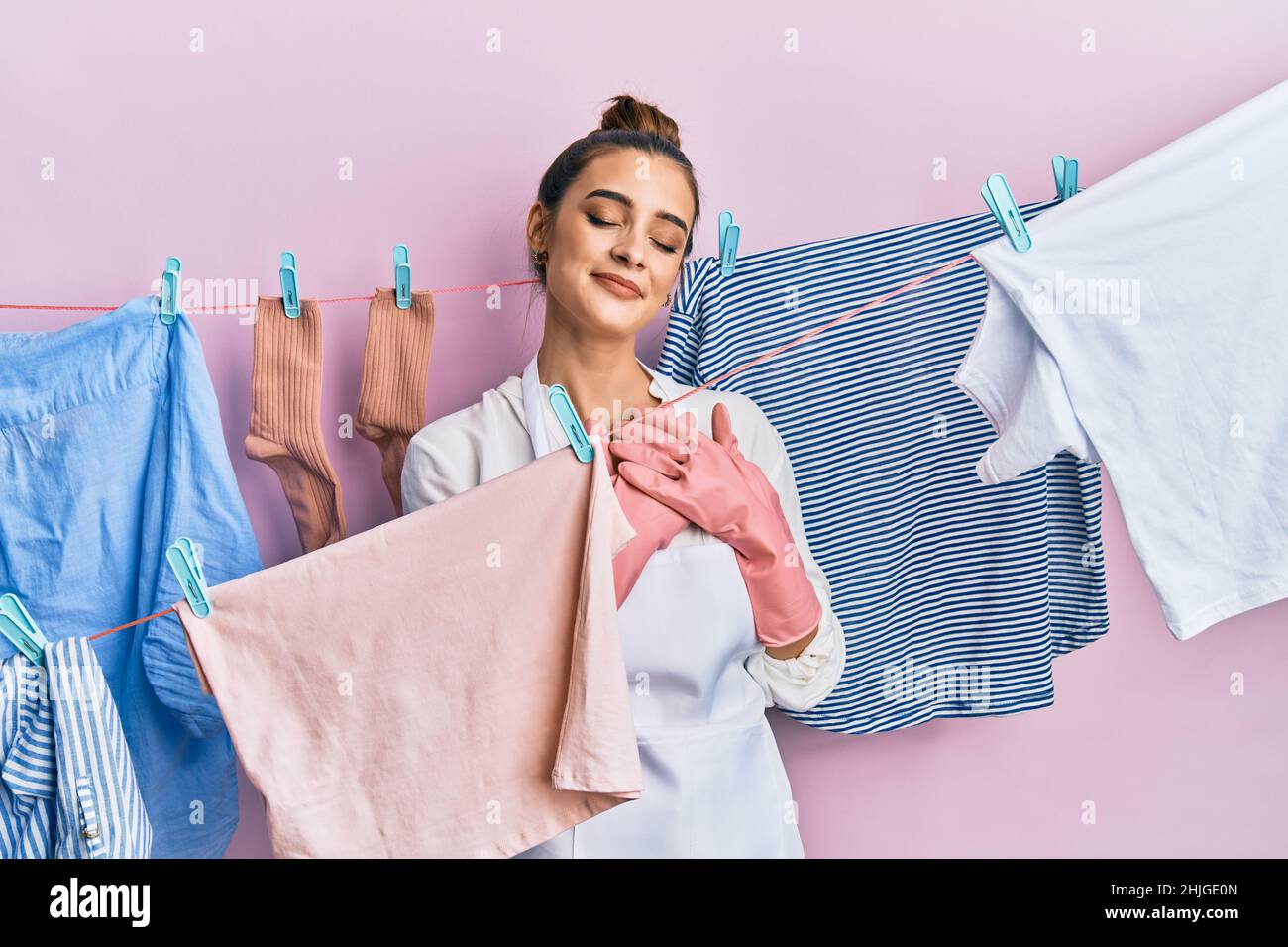 Beautiful brunette young woman washing clothes at clothesline smiling ...